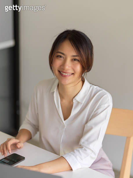 Beautiful Female Smiling To Camera While Sitting At White Desk In