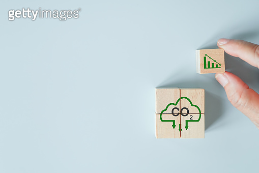hand holding wooden cube blocks with CO2 emission reduction icon for ...