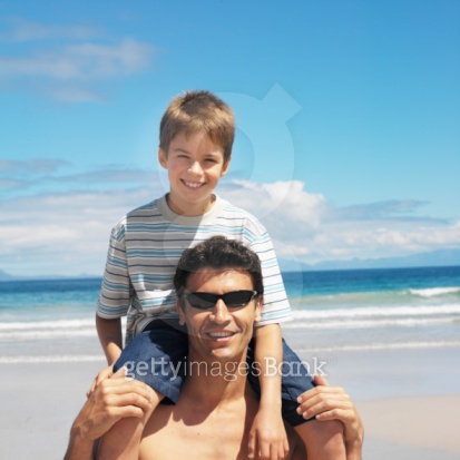 front view portrait of father giving son (8-9) piggyback on shoulders ...