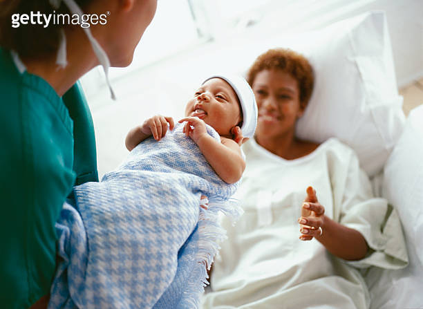 elevated close-up view of a doctor handing a new born baby to the ...