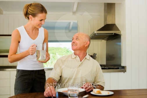Woman giving man a refill of his water 이미지 (78655629) - 게티이미지뱅크