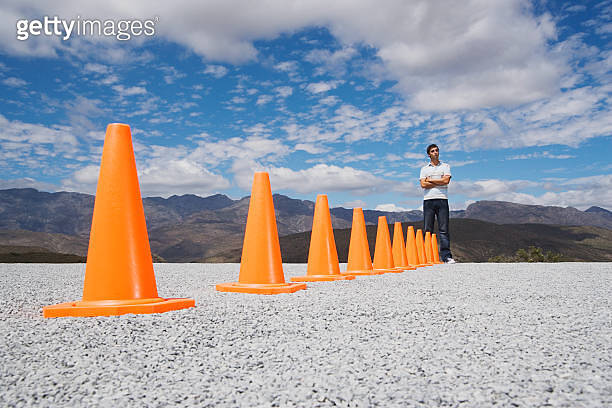 Man standing at the end of a row of safety cones (75592830) - 게티이미지뱅크
