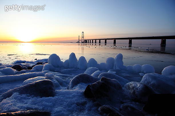 Frozen coastline and sunset at the Great Belt Bridge, Storebæltsbroen ...