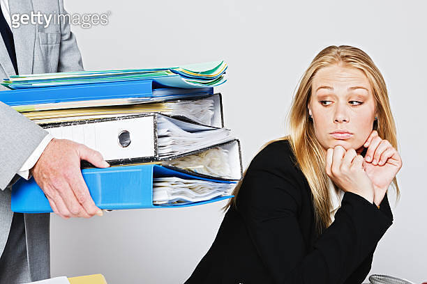 Businesswoman looks over shoulder nervously as even more work arrives ...