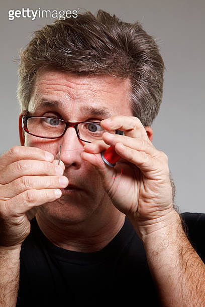 Studio shot of man with glasses threading a needle 이미지 (155356981) - 게티 ...