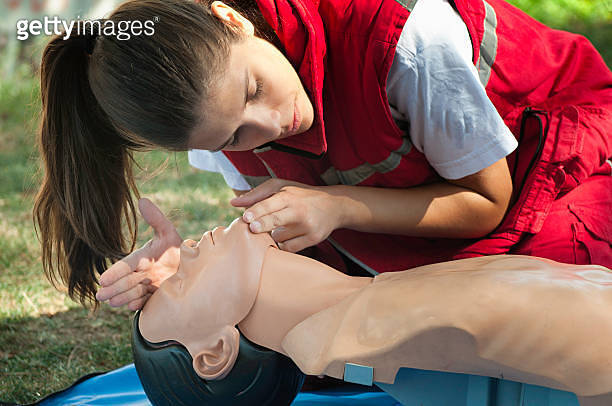 Woman in red vest performing CPR procedure on a dummy (171348544) - 게티이미지뱅크