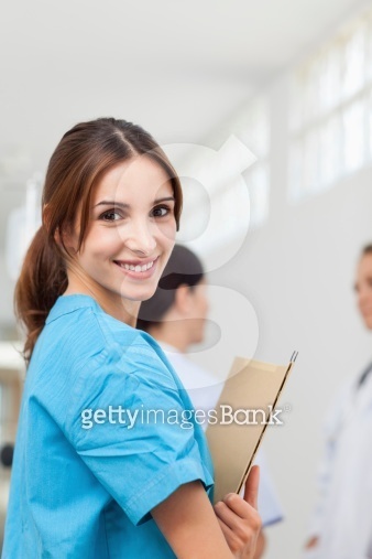 Nurse smiling while holding files and standing with a doctor (168647048 ...