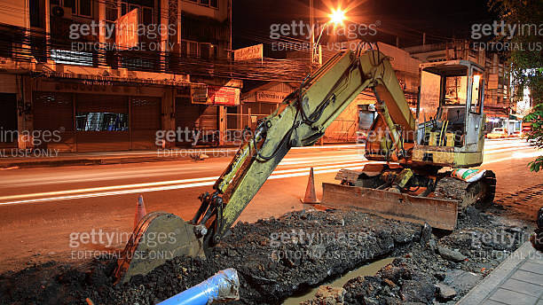 Yellow excavator digging street at night in Korat downtown (458276275 ...