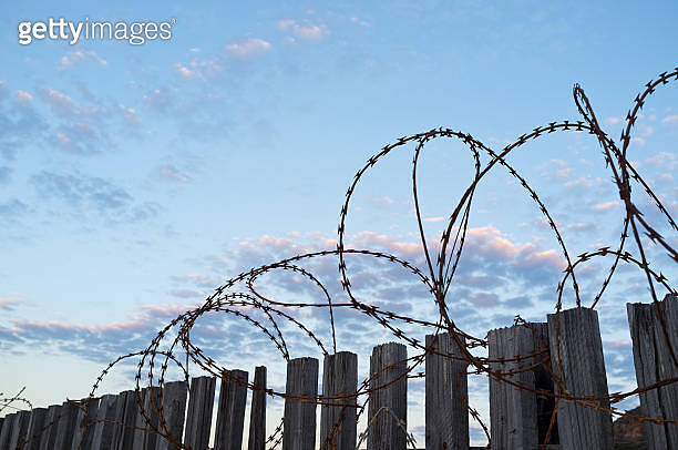 Rusty razor wire tops fence; blue sky behind promises freedom 이미지 ...