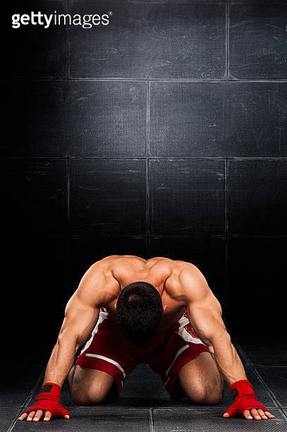 Fighter kneeling forward in front of a concrete wall 이미지 (180743762 ...