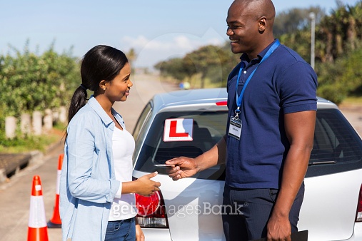 african driving instructor handing driving license to student driver ...
