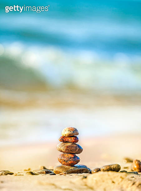 Stones pyramid on sand symbolizing peace and harmony, blue ocean ...