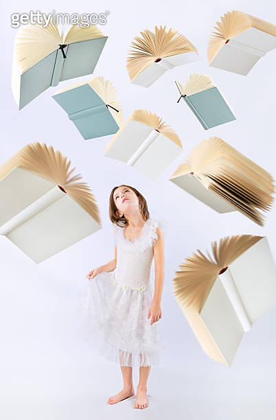 Flying books over little girl looking up 이미지 (475416963) - 게티이미지뱅크