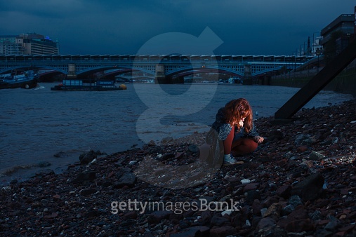 Woman beachcombing in city at night 이미지 (525044533) - 게티이미지뱅크