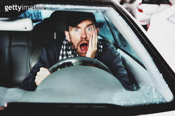 Horrified male driver looks through windshield, hand to face 이미지 ...