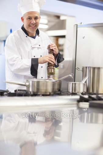 Cheerful head chef flavoring food with pepper (511508319) - 게티이미지뱅크