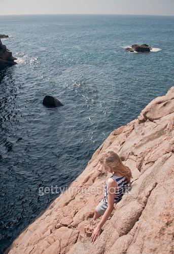 Young woman looking down into the ocean on the rocks 이미지 (521050367 ...