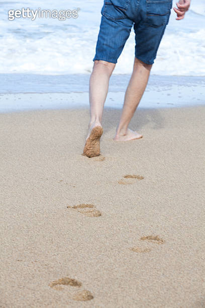 Man walks along shoreline making footprints in the sand 이미지 (481138549 ...