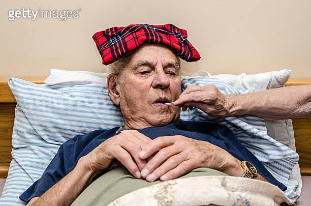 Sick old man in a bed with temperature being taken 이미지 (489779888) - 게티 ...