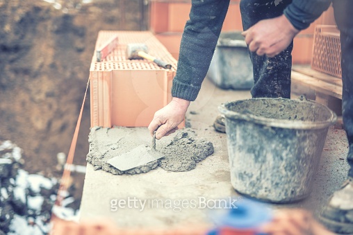 mason working with construction spatula and leveling mortar, creating ...