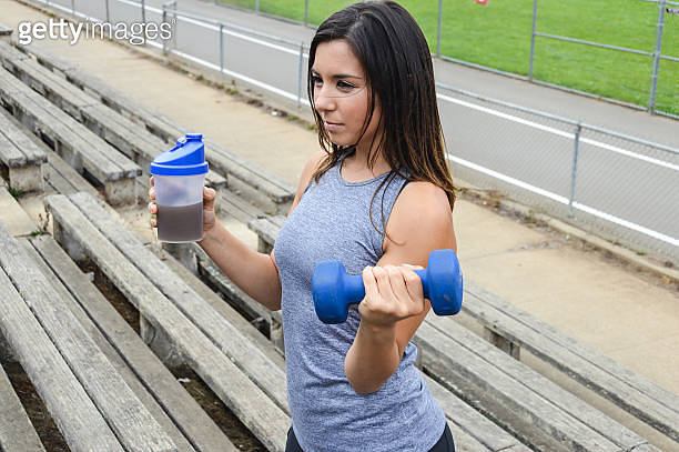 Woman drinking a protein shake and lifting weights 이미지 (494609860) - 게티 ...