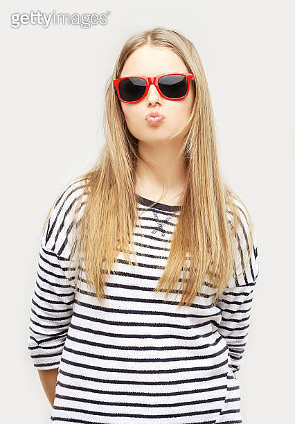 Girl pouting cheeks and blowing (469314452) - 게티이미지뱅크