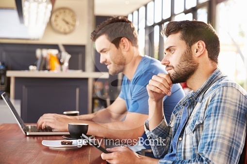 Two young men working on computers at a coffee shop (478407618) - 게티이미지뱅크