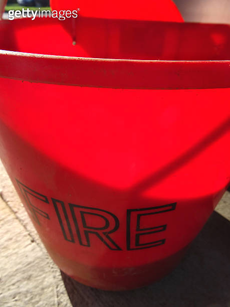 Red plastic fire-bucket filled with sand, petrol / gas fuel filling ...