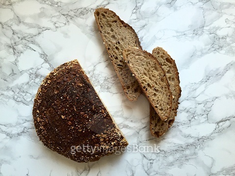 Round loaf of slow-fermented sourdough whole-grain bread with slices ...