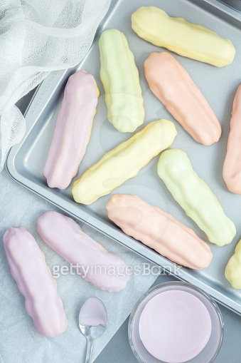 Homemade eclairs with pastel color icing on a baking sheet 이미지 ...