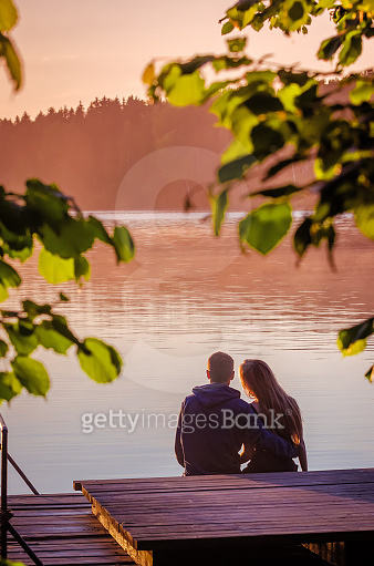 Romantic couple sitting on pier enjoying stunning sunset 이미지 (585786002 ...