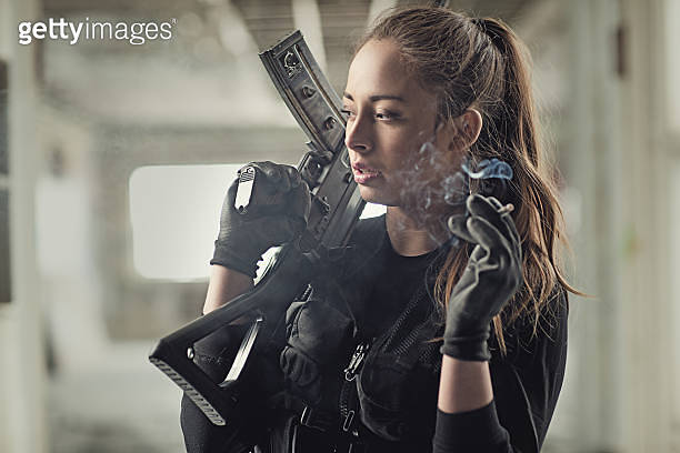 Female military swat team member holding rifle in abandoned warehouse ...