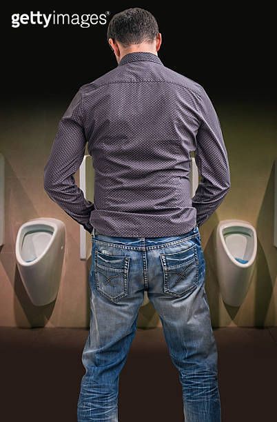 Standing man peeing to a urinal in restroom (587227054) - 게티이미지뱅크