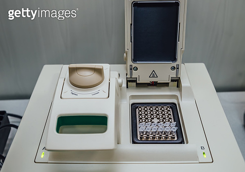 Opened polymerase chain reaction (PCR) cycler machine with DNA samples ...