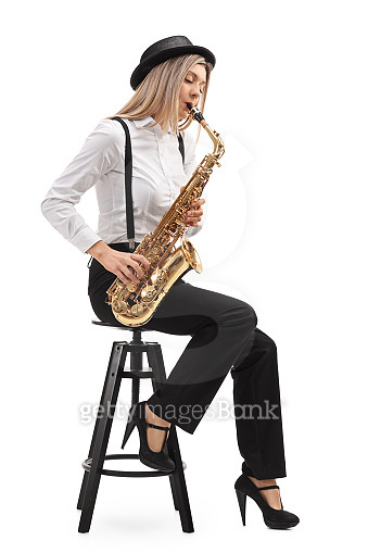 Female jazz musician seated on a chair playing a saxophone (690009764 ...