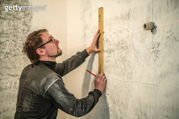 Manual construction worker doing the markup on the wall for the further ...