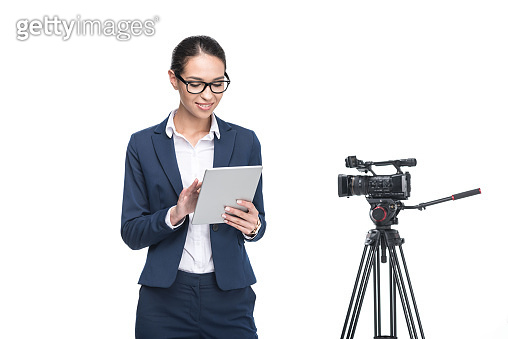 female television reporter using digital tablet standing near video ...