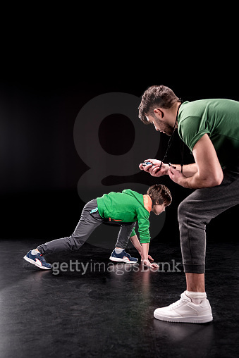 side view of man controlling time while boy training on black 이미지 ...