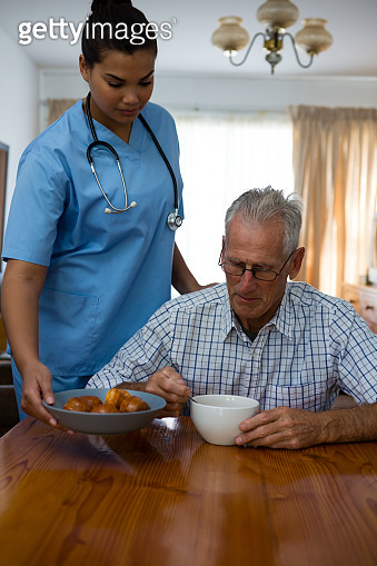Doctor serving food to senior man at table in nursing home (830307106 ...