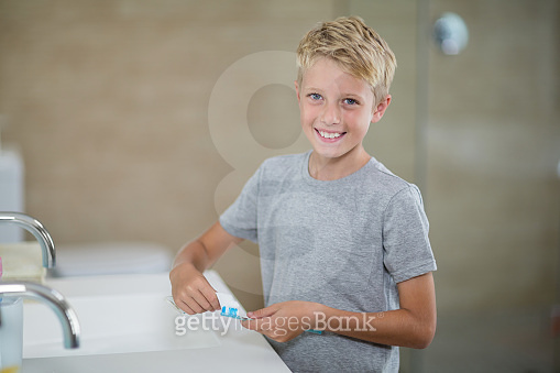 Portrait of boy putting toothpaste on brush in bathroom (678455706 ...