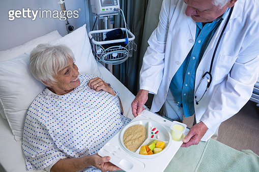 Doctor serving breakfast and medicine to senior patient (651368808 ...