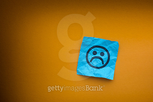 Blue paper note with sad face on a yellow paper background (639688888 ...