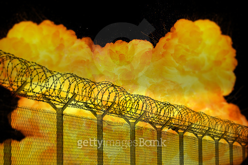 Realistic orange fire explosion behind restricted area barbed wire ...