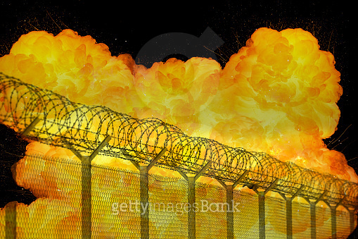 Realistic orange fire explosion behind restricted area barbed wire ...