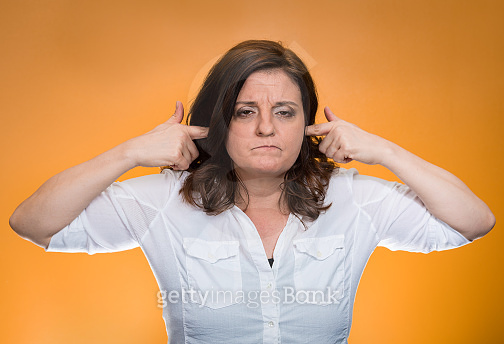 mature woman covering plugging ears annoyed by loud noise ignoring ...