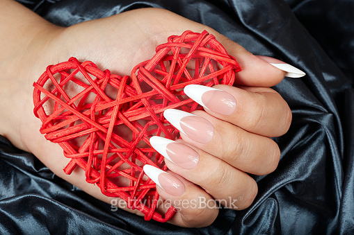 Hand with long artificial french manicured nails holding a heart ...