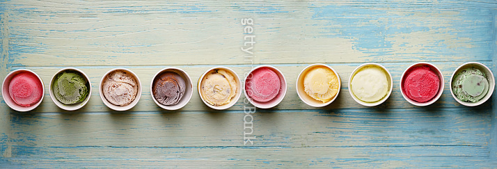 Row of assorted flavors and colors of gourmet Italian ice cream on wood ...