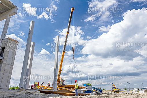 Mobile crane is carry pile of concrete armature, rusty square ...