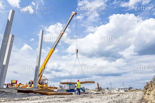 Mobile crane is carry pile of concrete armature, rusty square ...