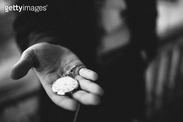 Close-up of a man checking the time on a pocket watch (871888850) - 게티이미지뱅크